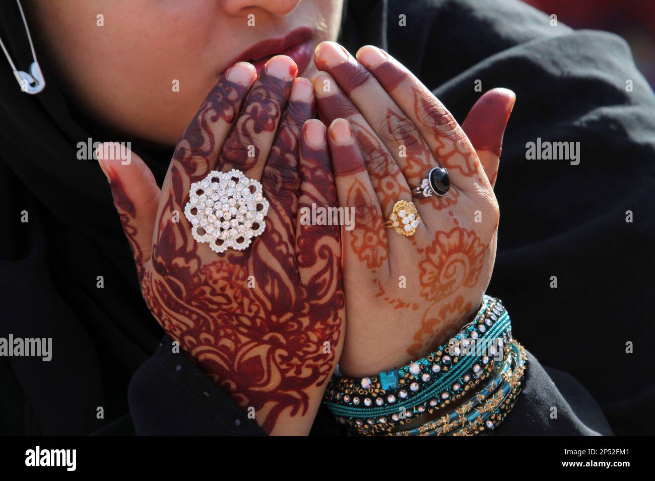 A Pakistani worshipper wearing henna designs on her hands prays at the ...