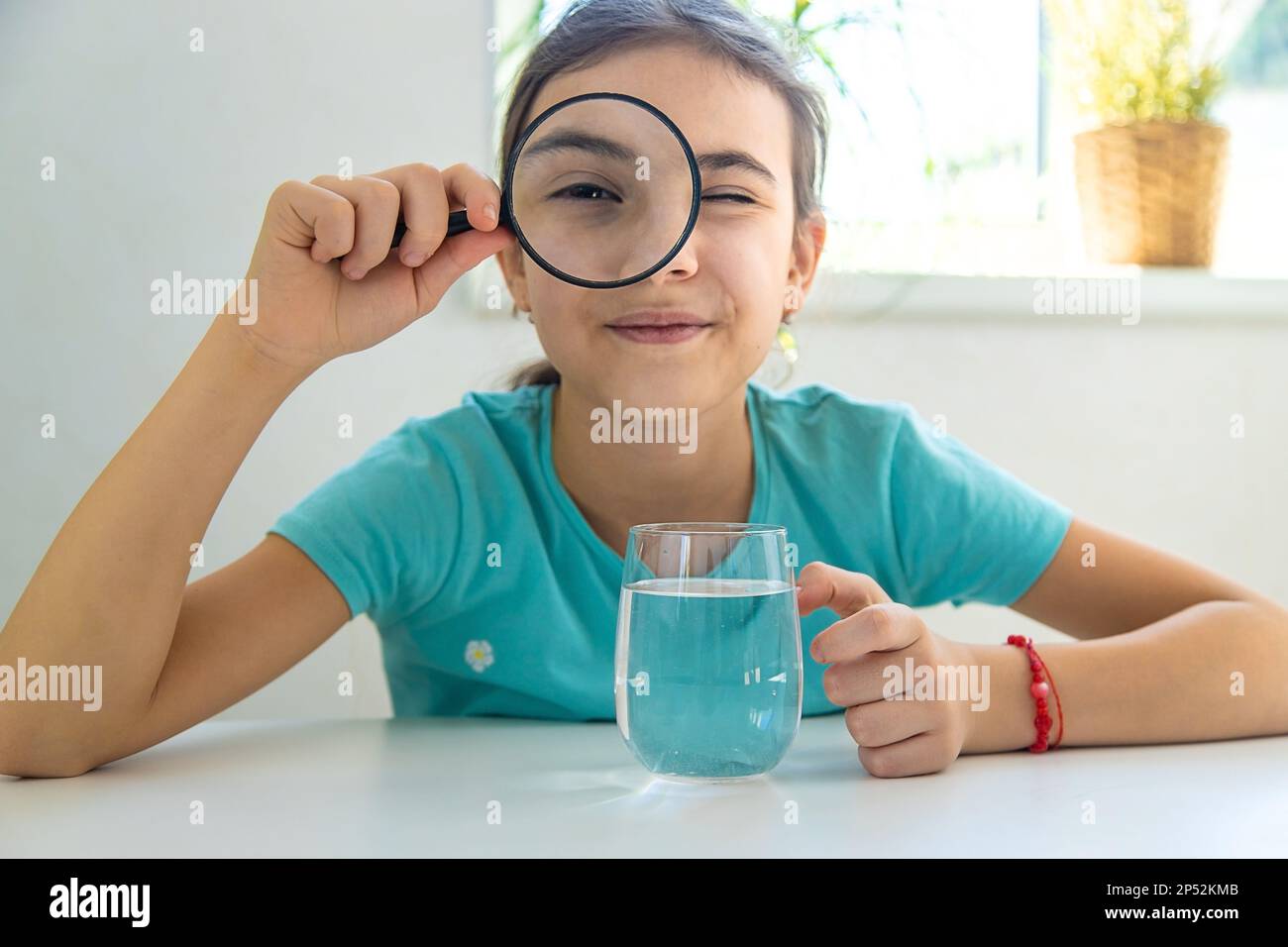 The child examines the water under a magnifying glass. Selective focus ...