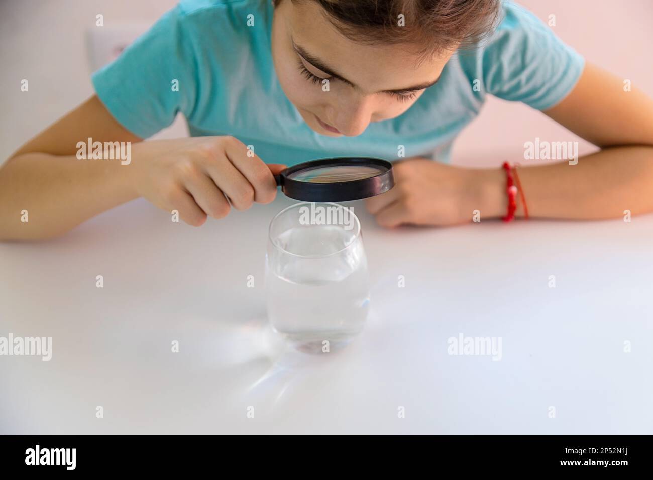 The child examines the water under a magnifying glass. Selective focus ...