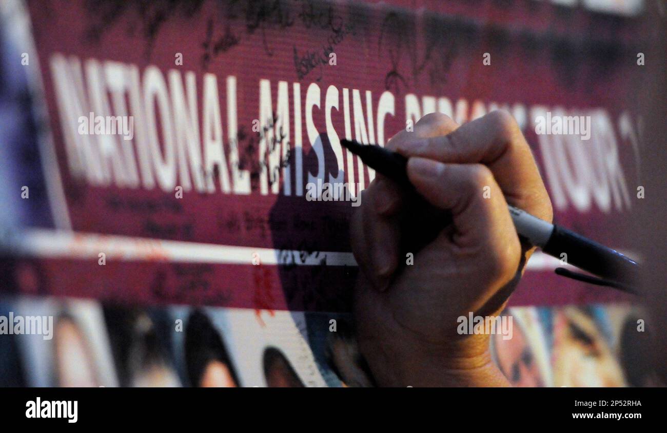 People signed a banner with photos of those being remembered at the CUE ...
