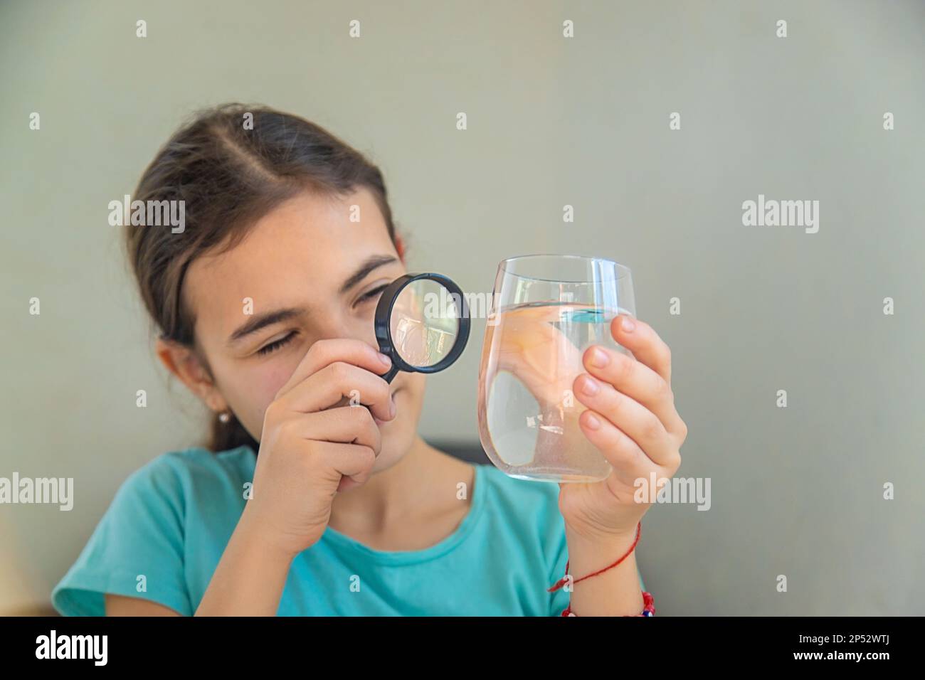 The child examines the water under a magnifying glass. Selective focus ...