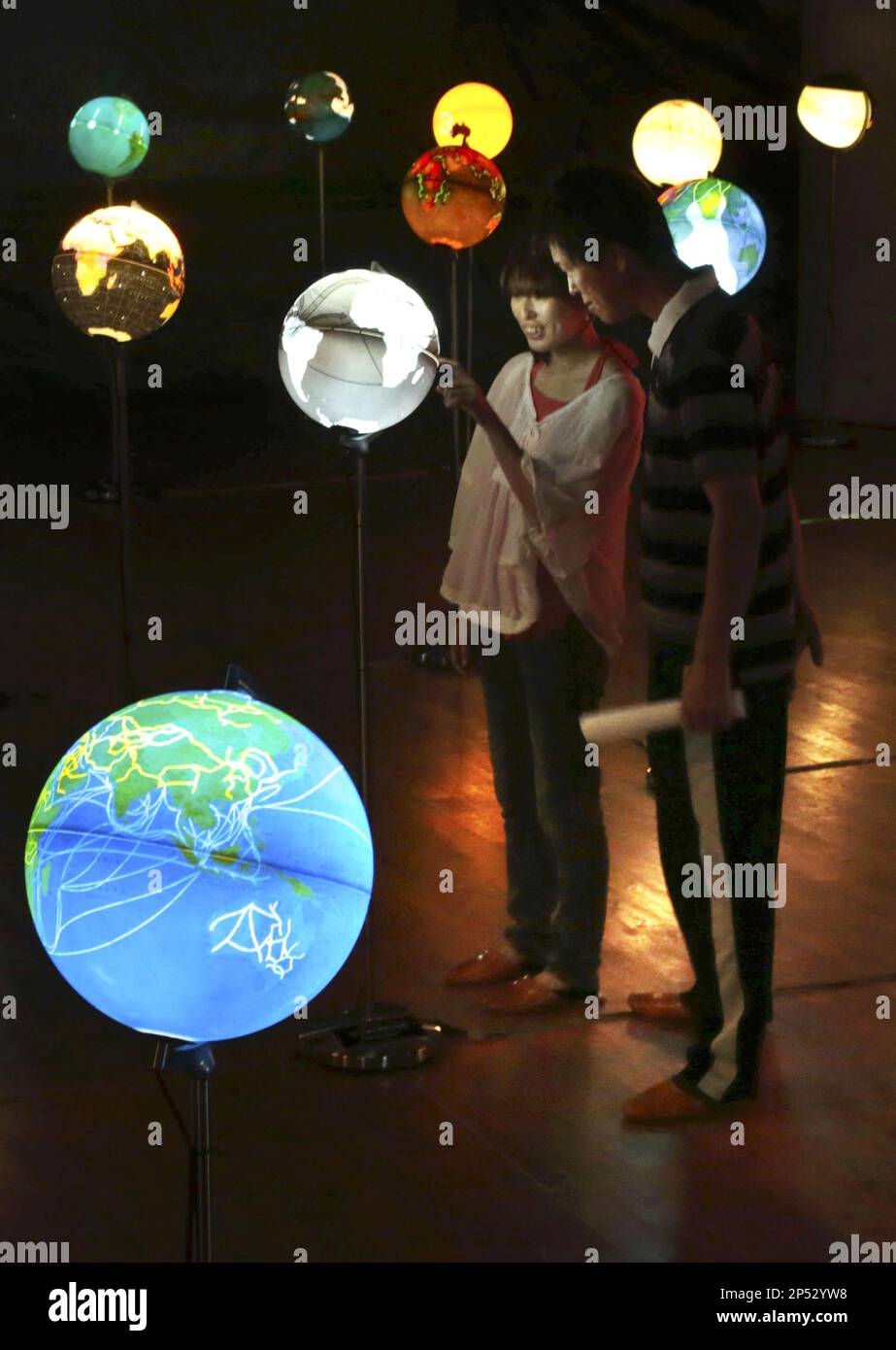 Visitors look at world globes at an enviromental art exhibition by Ingo ...