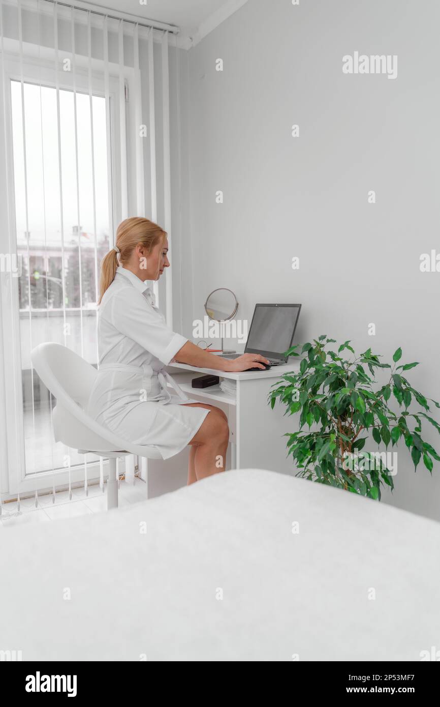 Blonde doctor in the doctor's office smiling. On the table is a ...