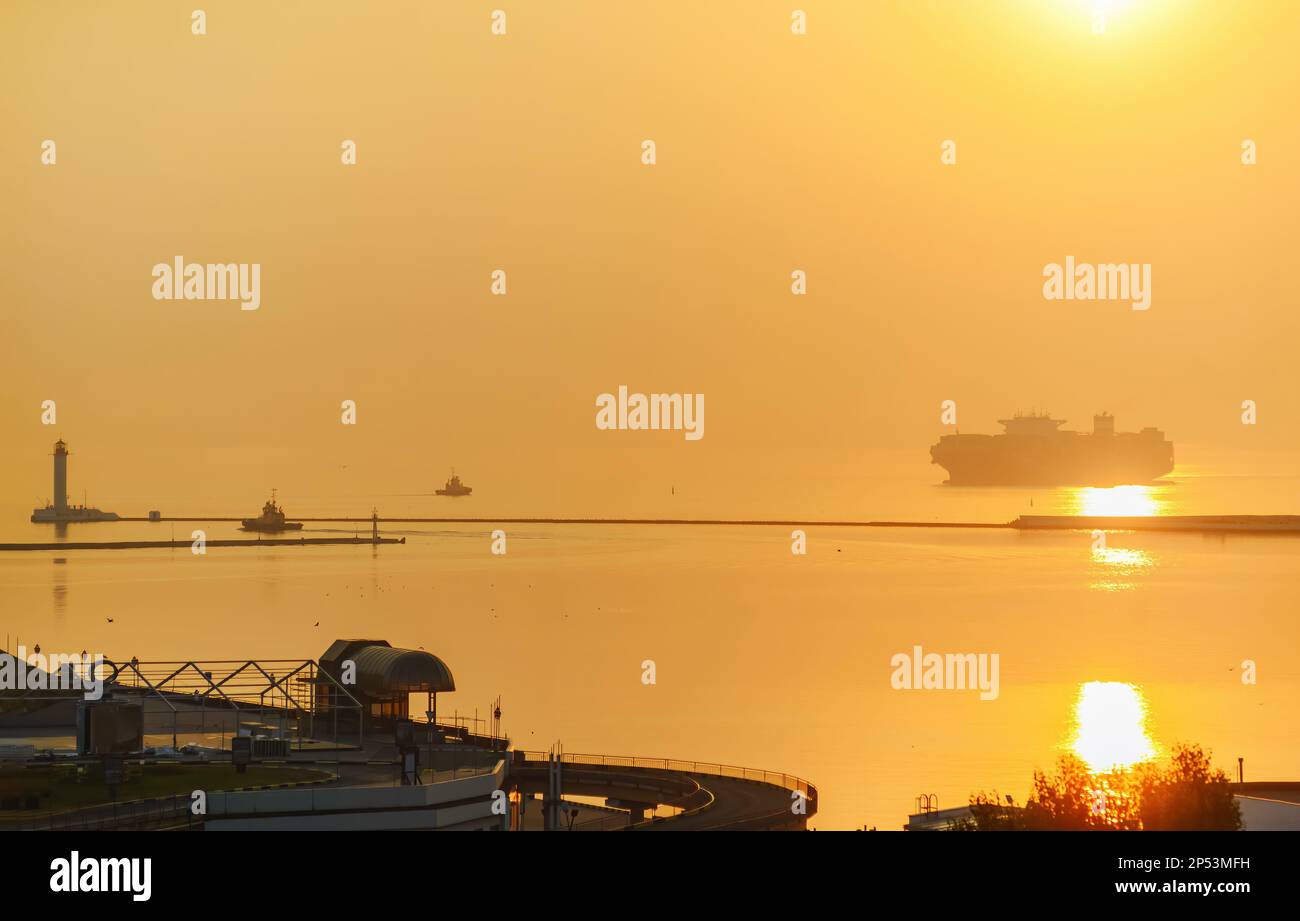 Container ship arrives a port during beautiful sunset along coastline ...