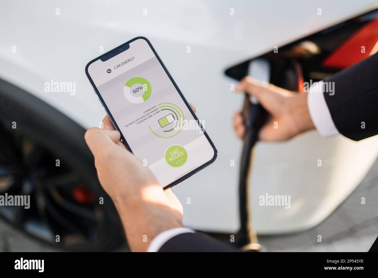 Close up of businessman charging electric car on station and checking ...