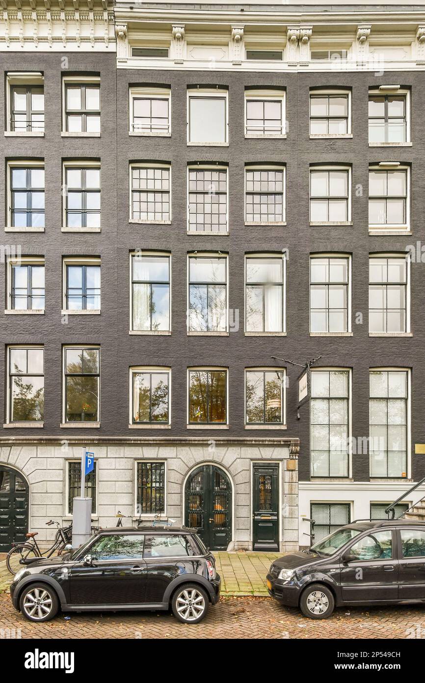 two cars parked in front of a large building with many windows on the ...