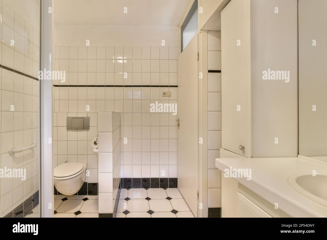 a small bathroom with black and white tiles on the floor, walls, and ...
