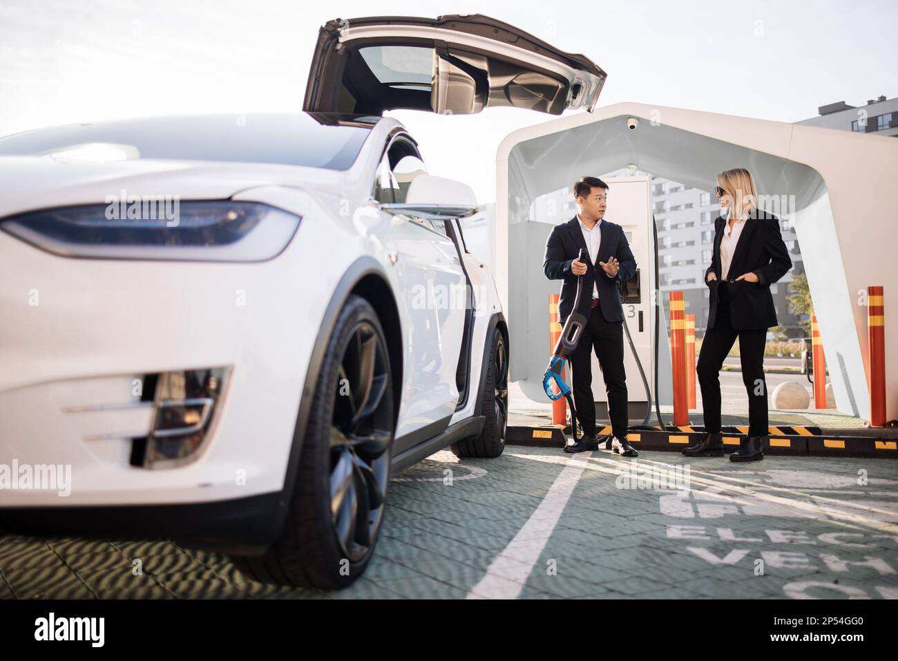 Stylish caucasian woman talking with asian car dealer while buying new ...