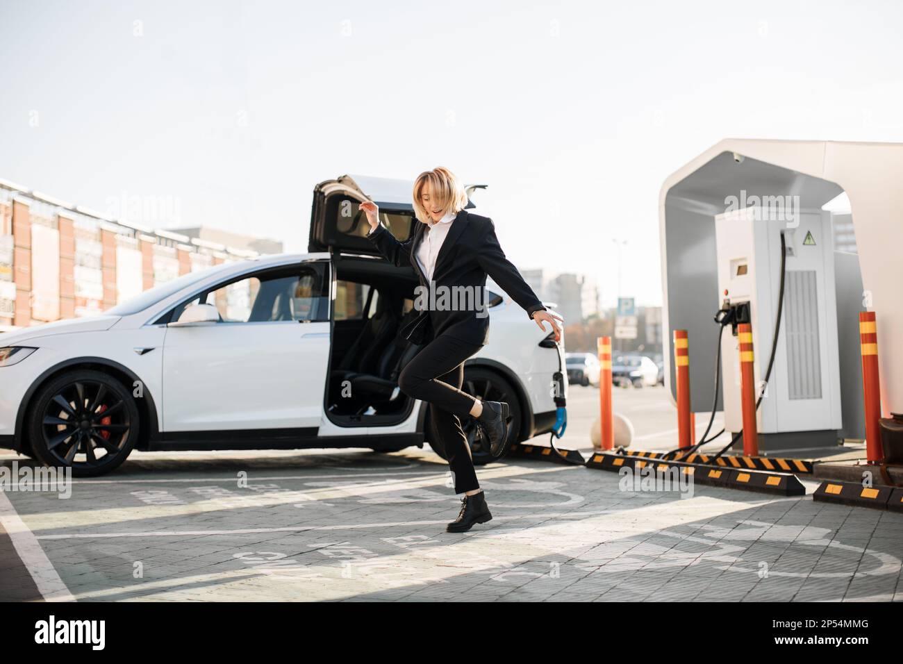 Charming young woman in business suit dancing joyfully outdoors while ...