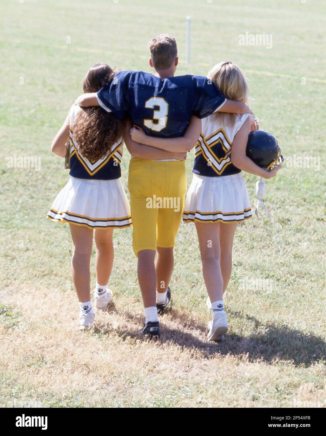 A young football player walks off the field with his arms around a ...