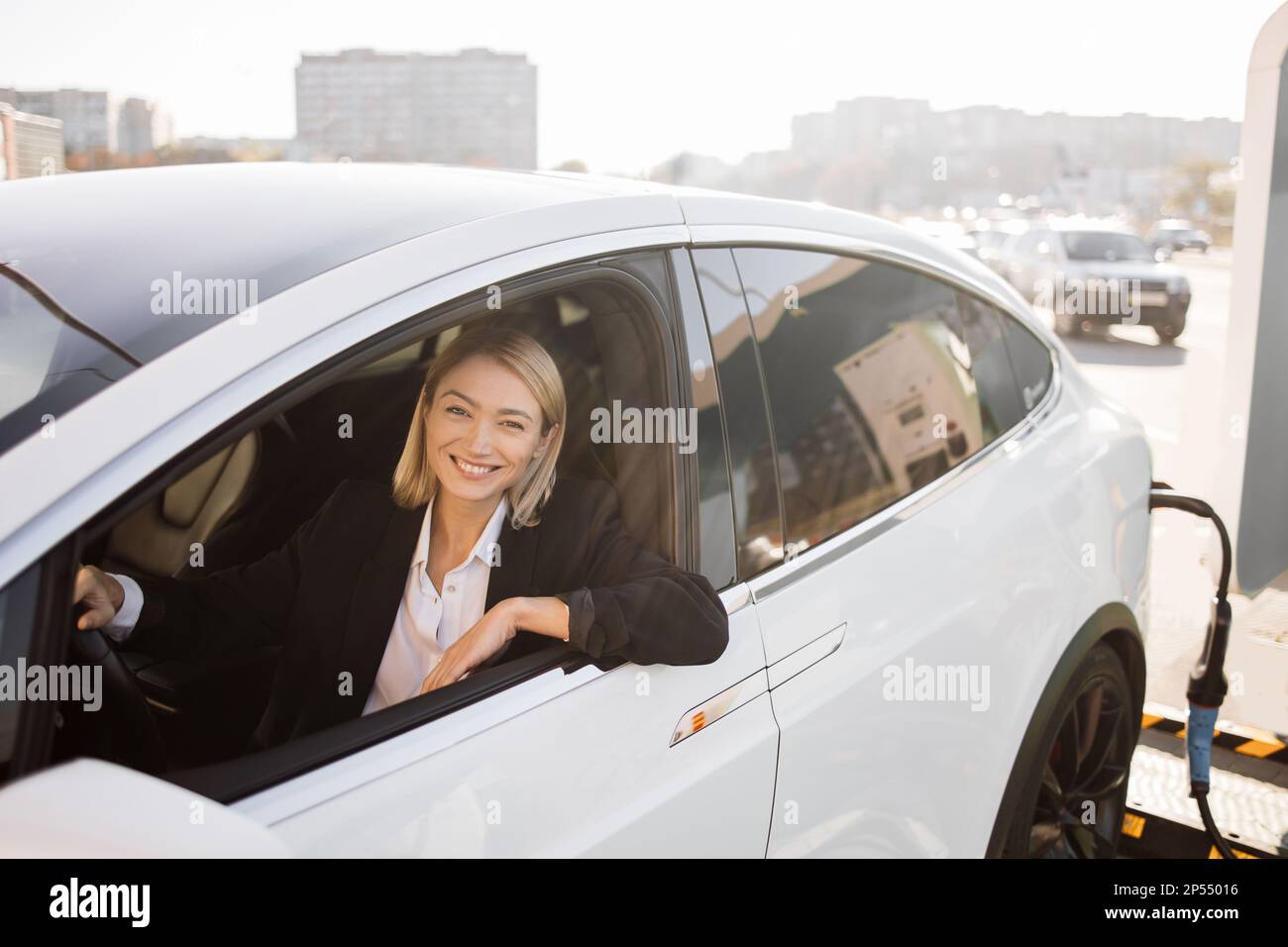 Caucasian woman sitting on driver seat in luxury car and smiling on ...