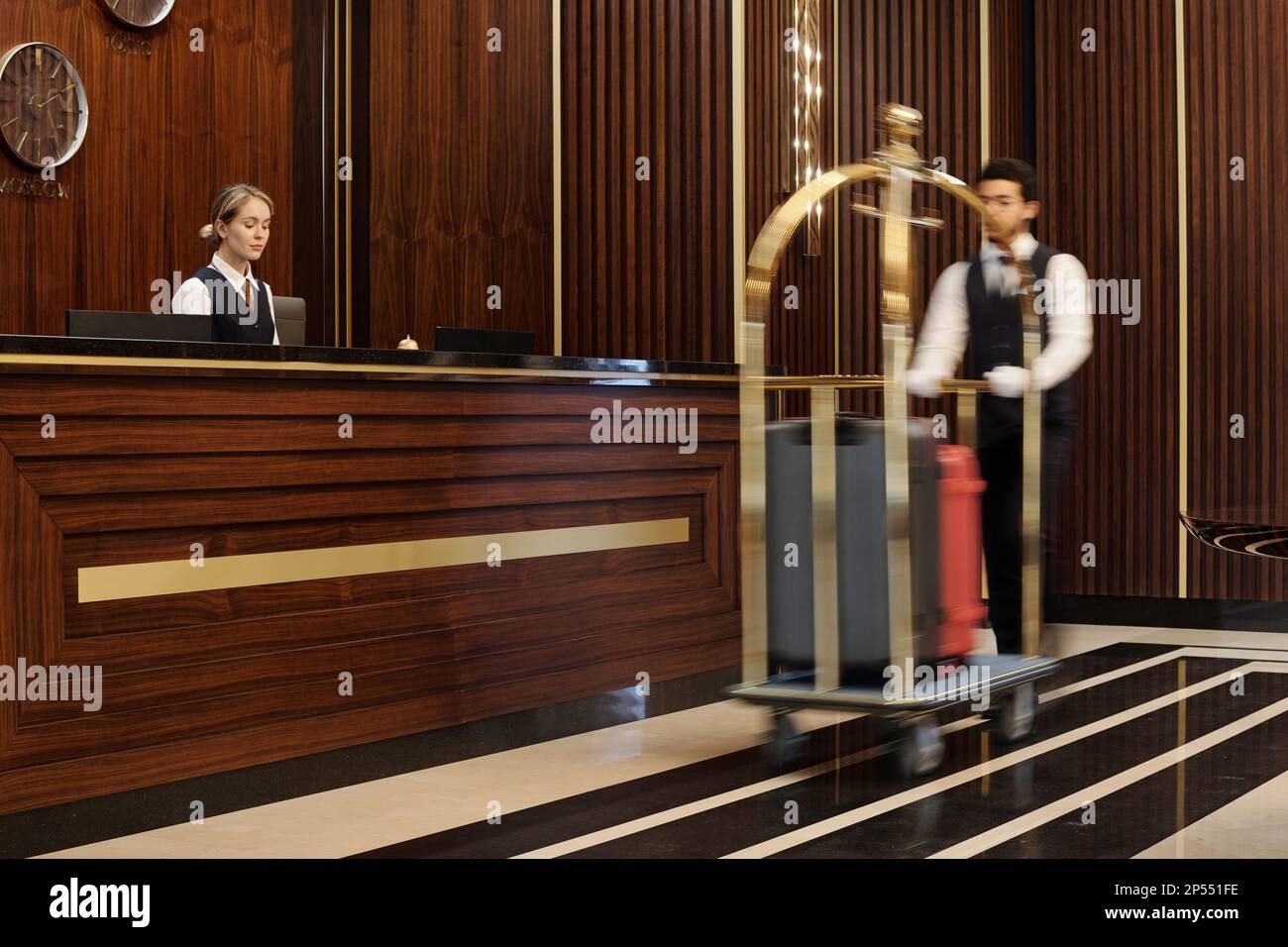 Blurry motion of bellboy pushing cart with clients luggage while ...