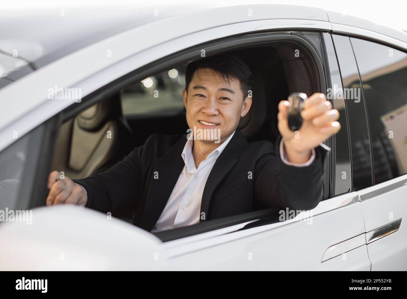Satisfied asian man in business suit showing car keys while sitting ...