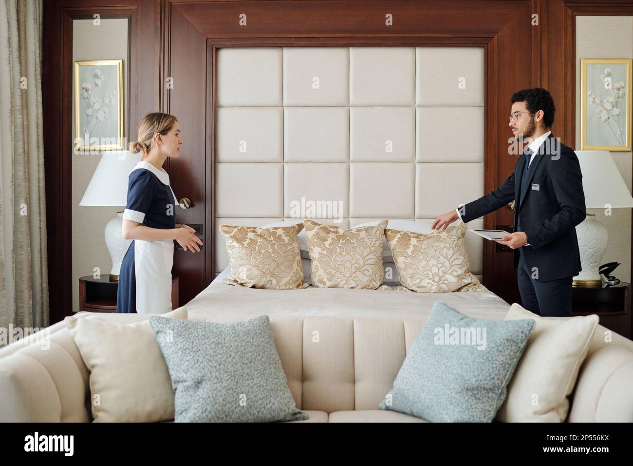 Young housekeeping manager of five star hotel instructing chambermaid ...