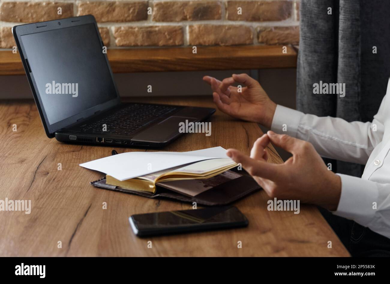 A businessman meditates while working on a laptop, sitting with his ...