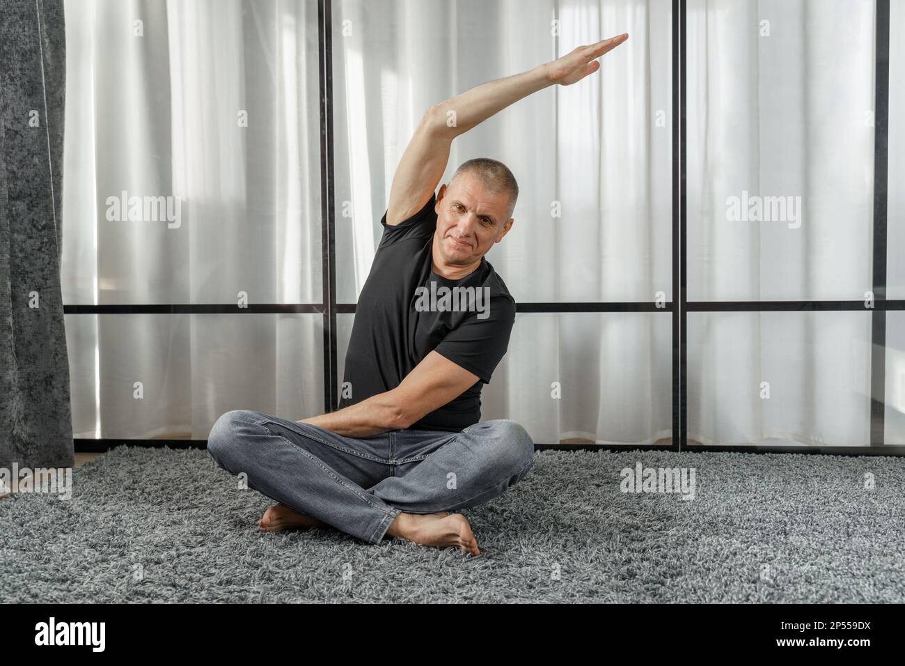 A man sits on a mat and does yoga, does exercises. Healthy lifestyle ...