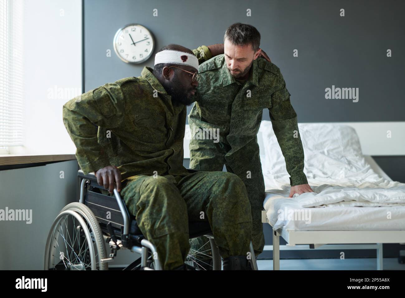 Soldier in military uniform helping his injured friend with bandage on ...