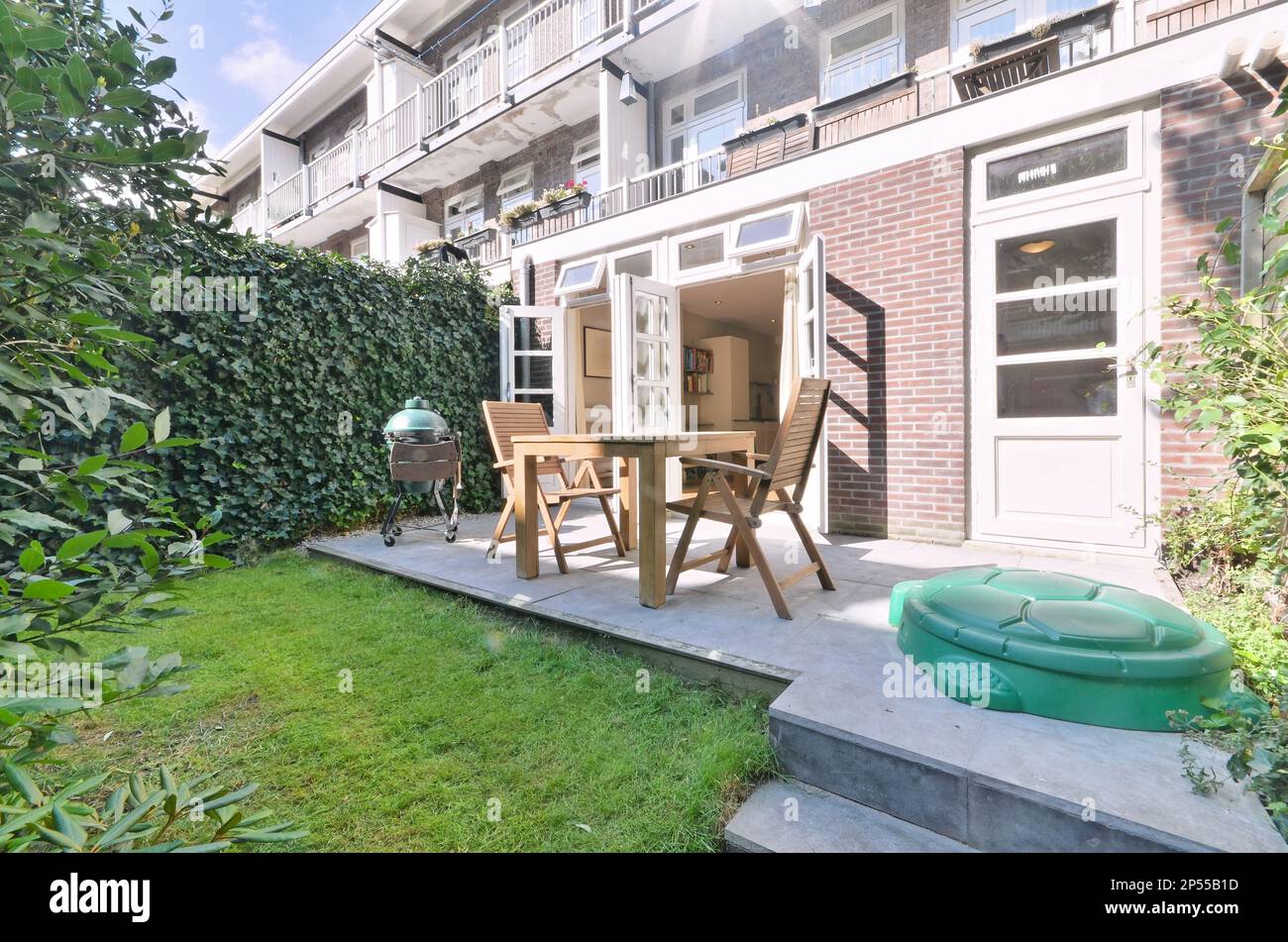 a patio with chairs and table in the back yard next to an apartment ...