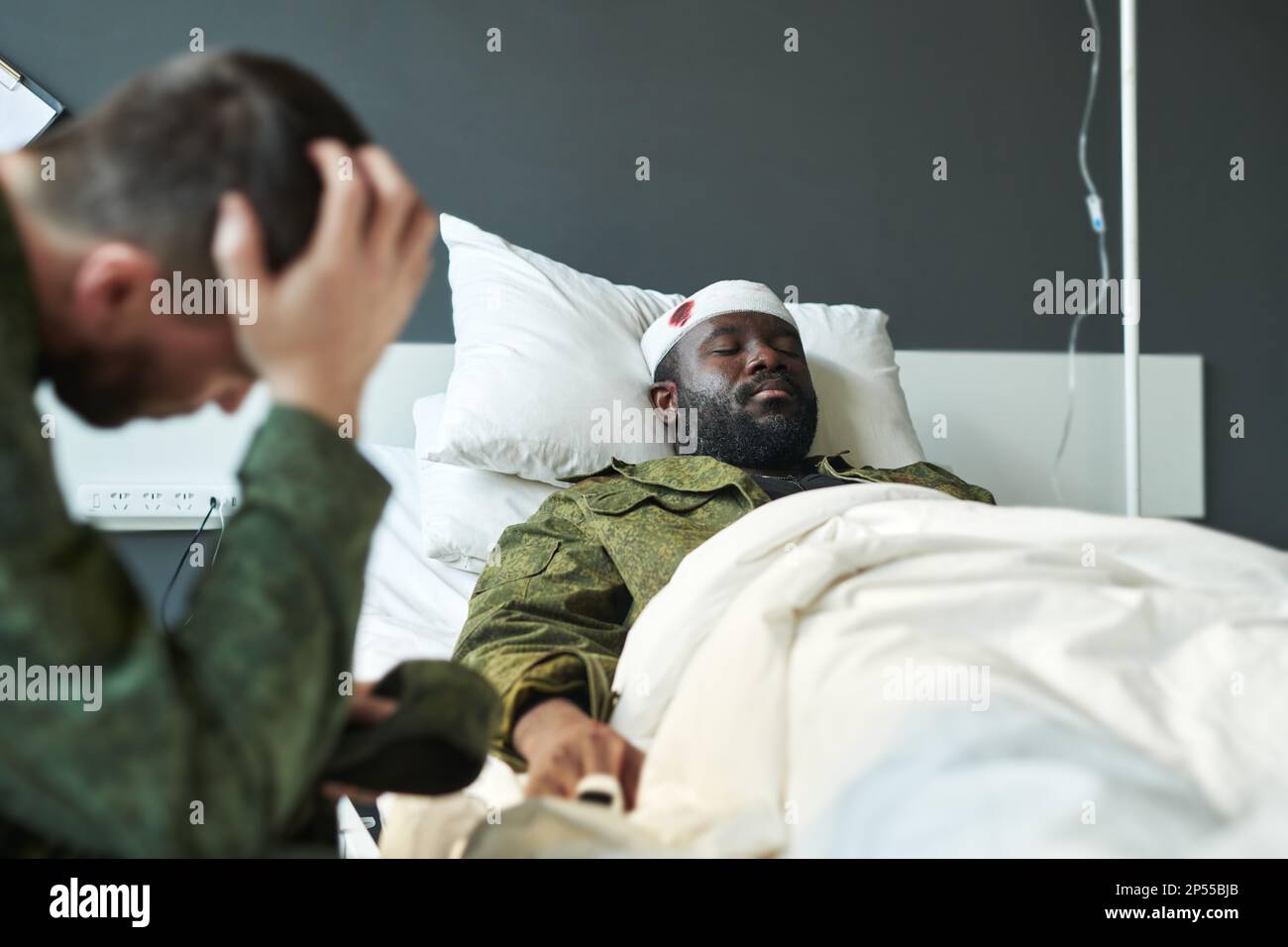 Young wounded African American soldier in military uniform lying in ...