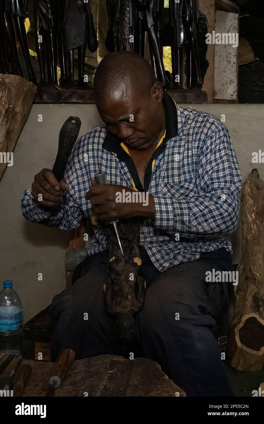 Karatu, Tanzania - October 16th, 2022: A man carving wood, using a ...