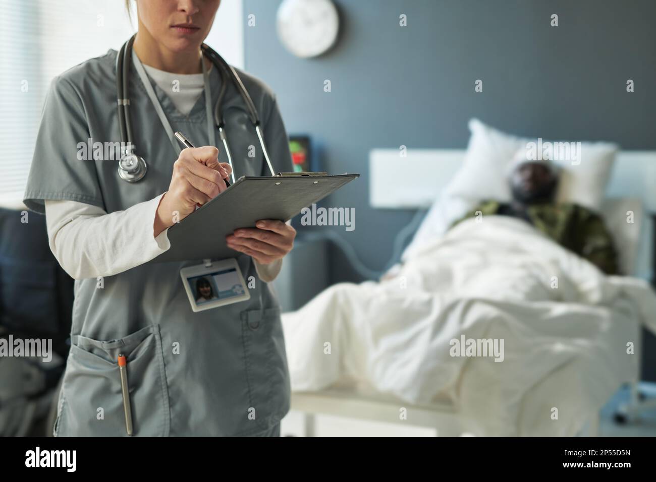 Close-up of young nurse in medical scrubs making medical prescriptions ...