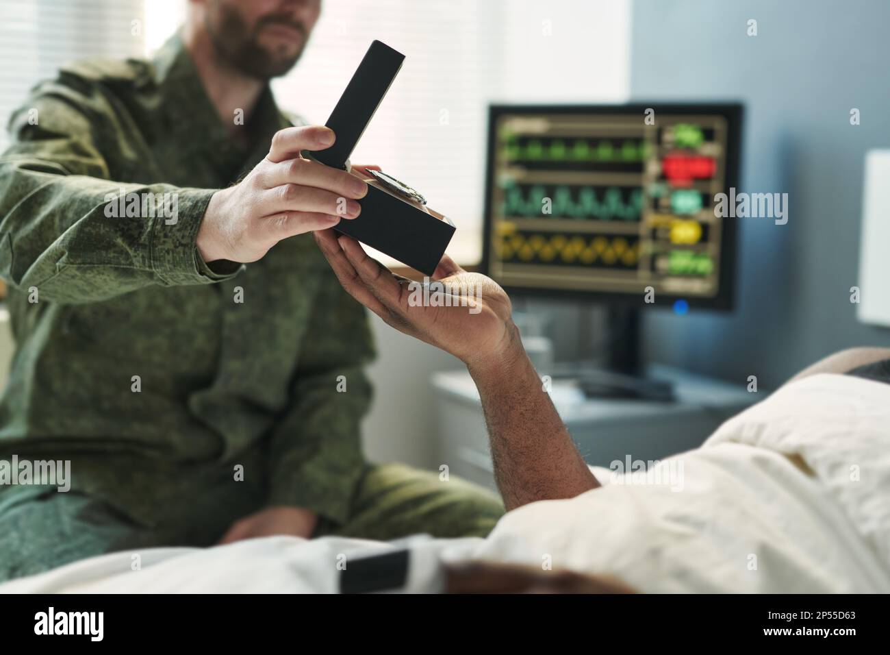 Hand of young African American injured soldier taking small box with ...