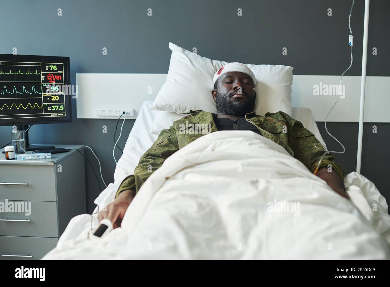 African American soldier with his head wrapped by bandage lying in bed ...