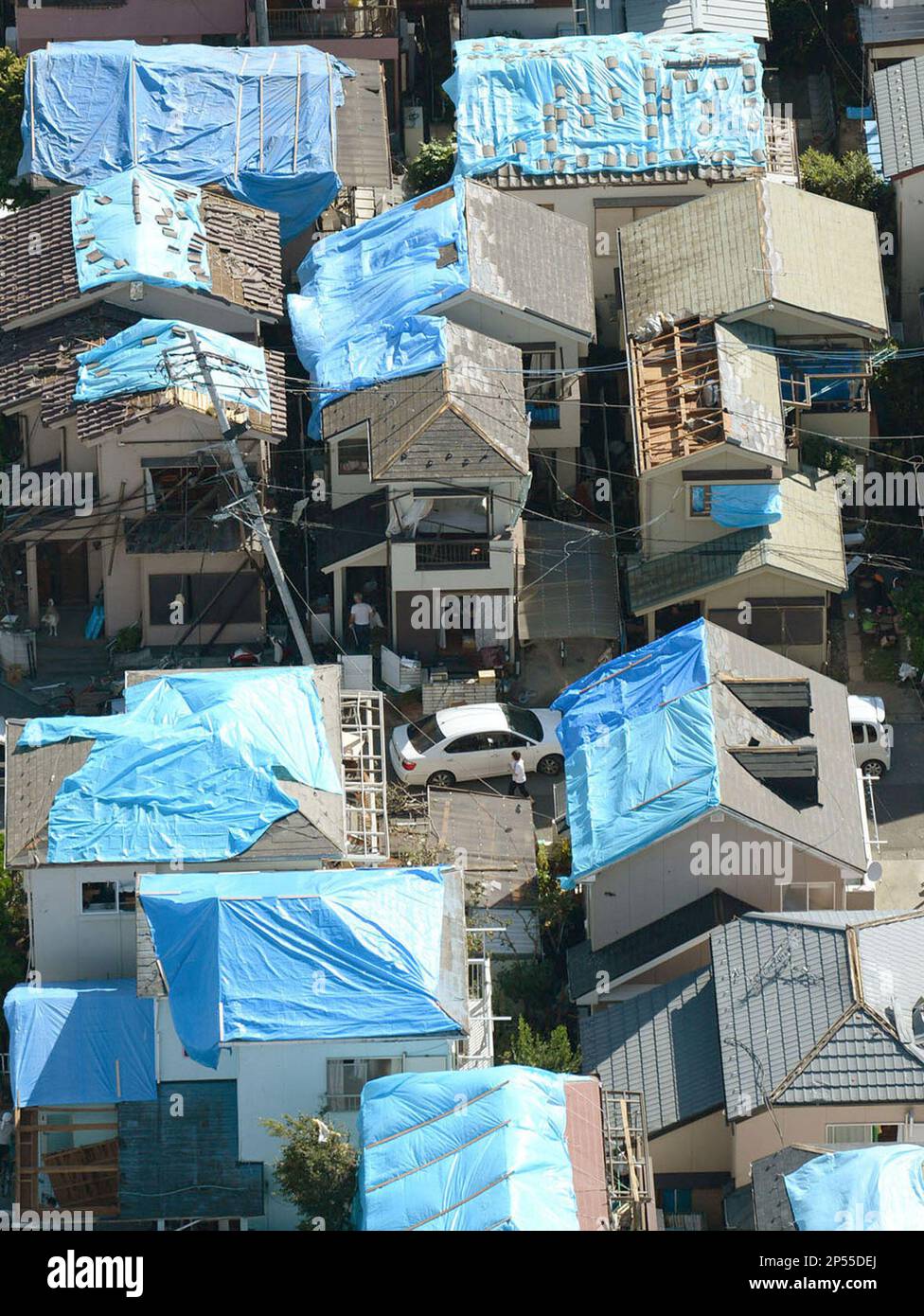 This aerial photo shows damaged houses covered with blue plastic sheets ...