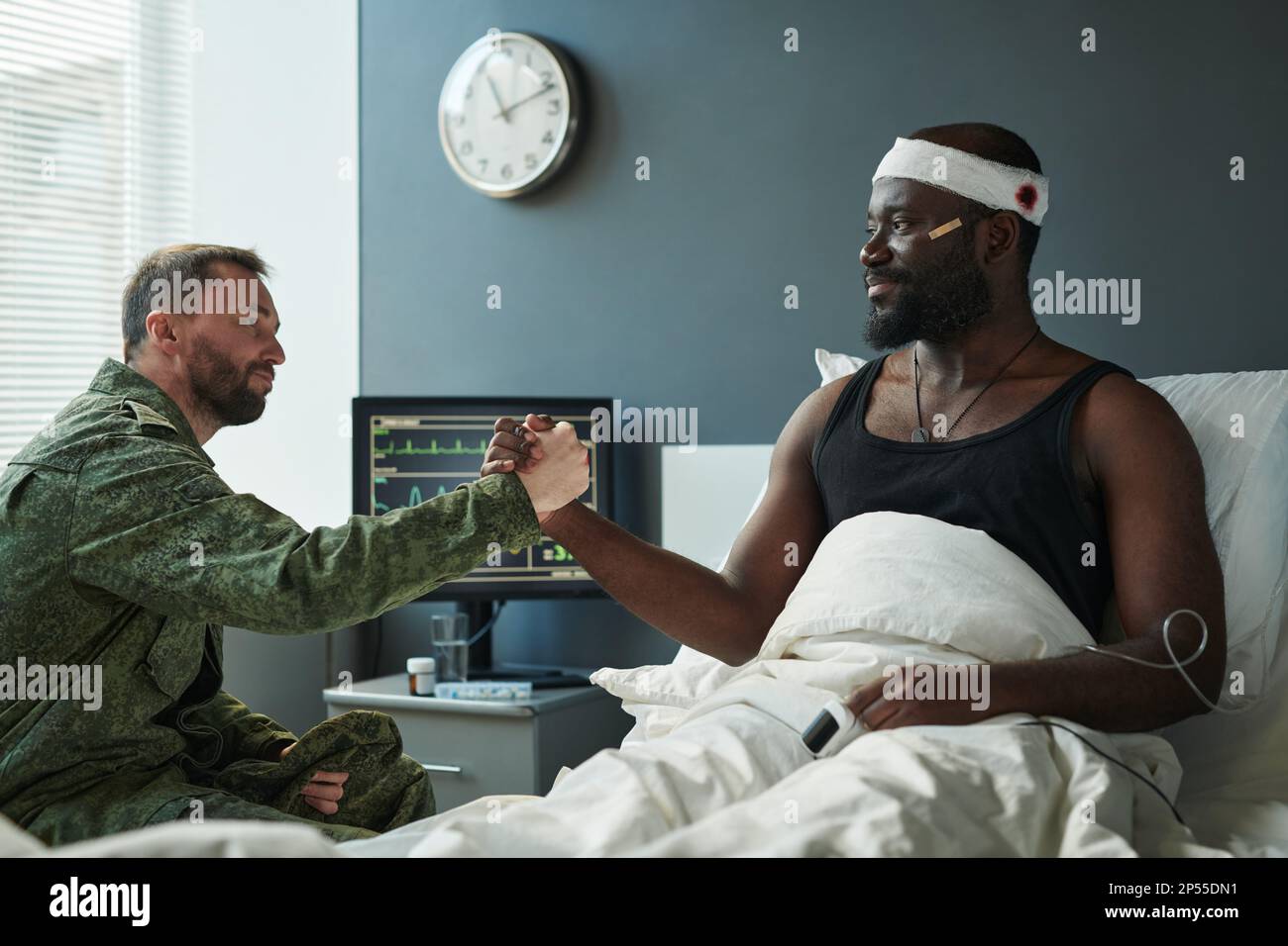 Young African American soldier with wounded head and his friend ...
