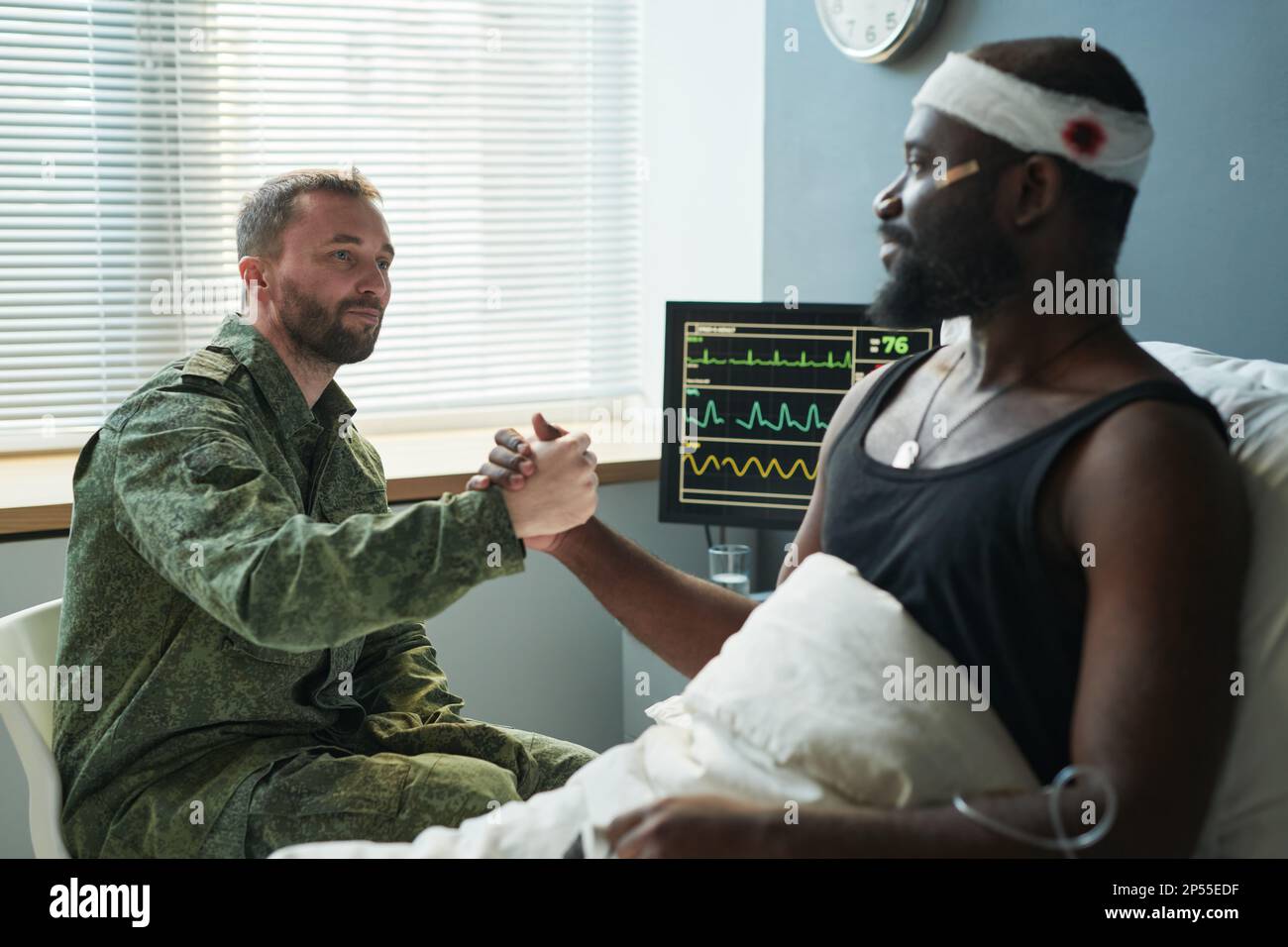 Focus on young soldier in military uniform shaking hand of African ...