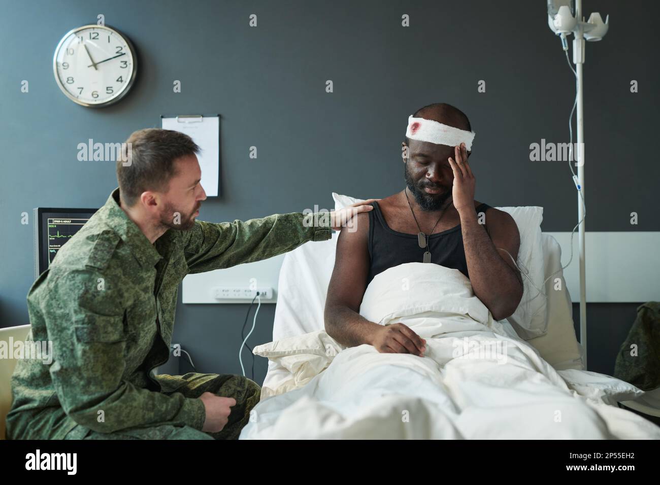 Young man in military uniform supporting his injured friend sitting on ...