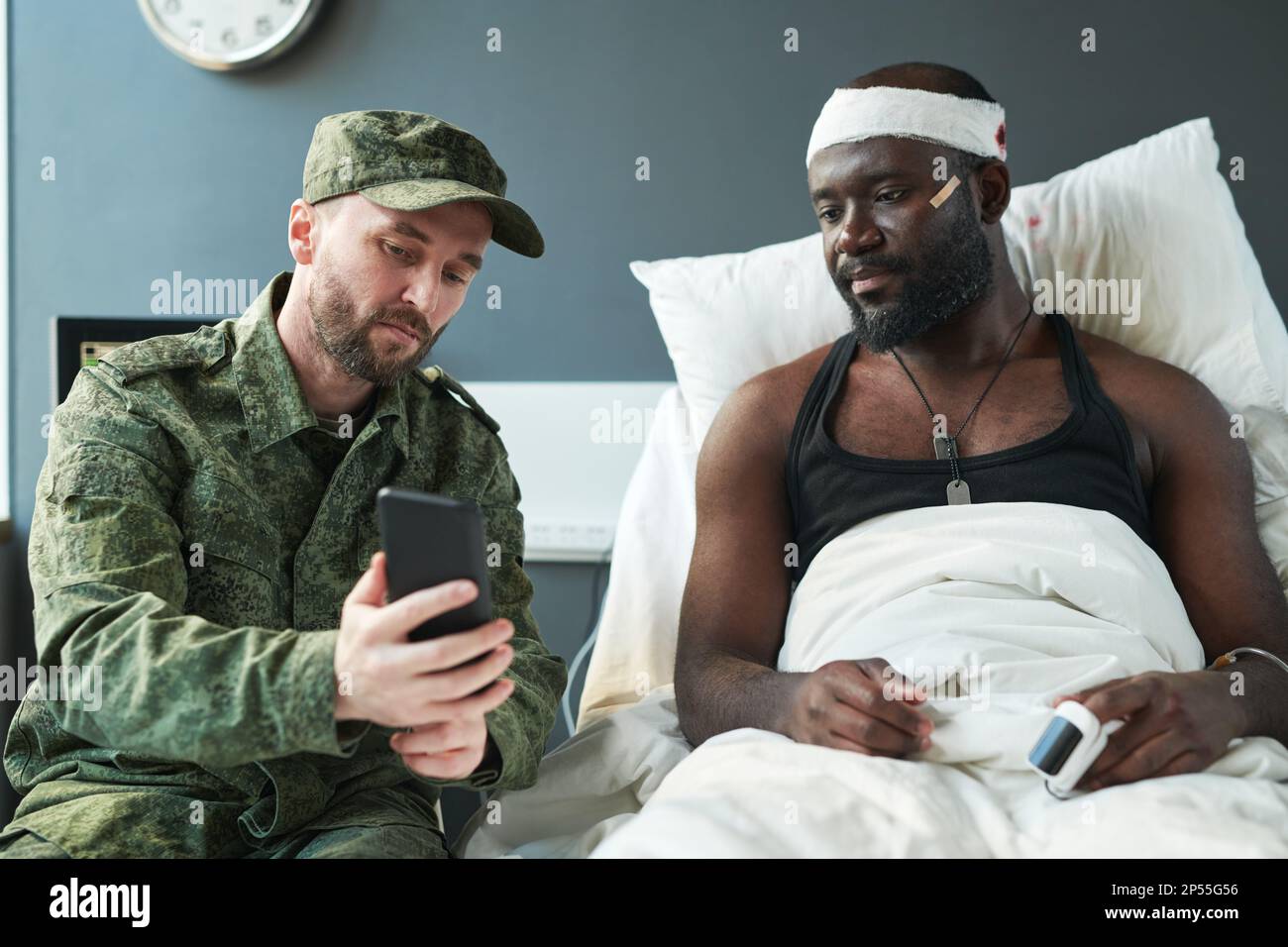 Young soldier in military uniform showing new photos in smartphone to ...