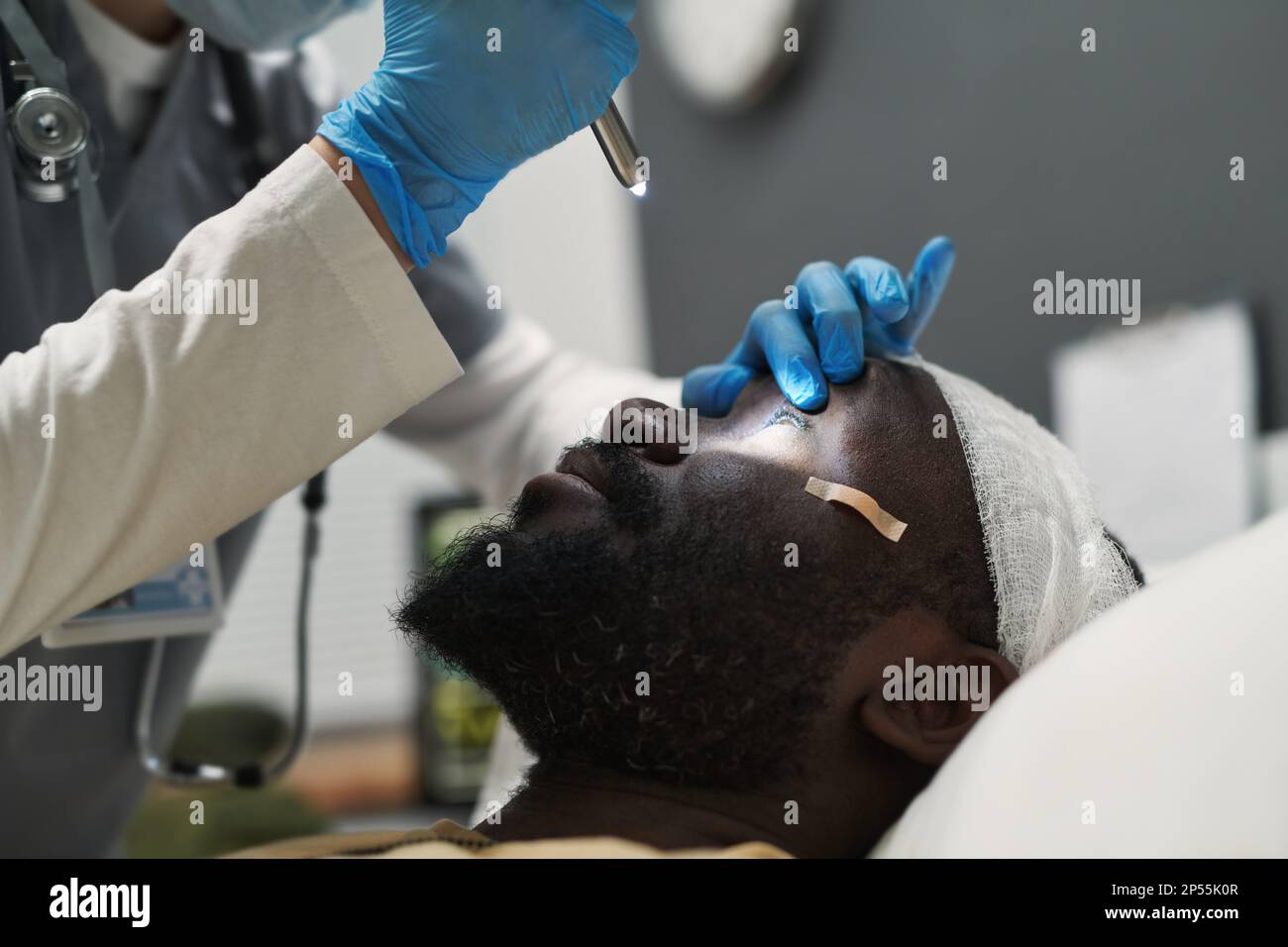 Close-up of doctor or nurse opening eye of injured patient while ...