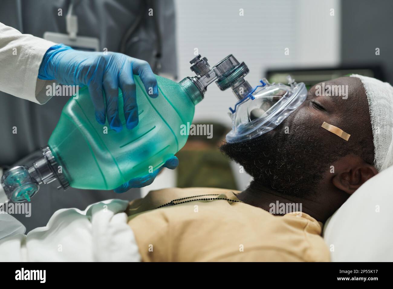 Close-up of sick man or injured soldier lying in bed in military hospital while breathing with ...
