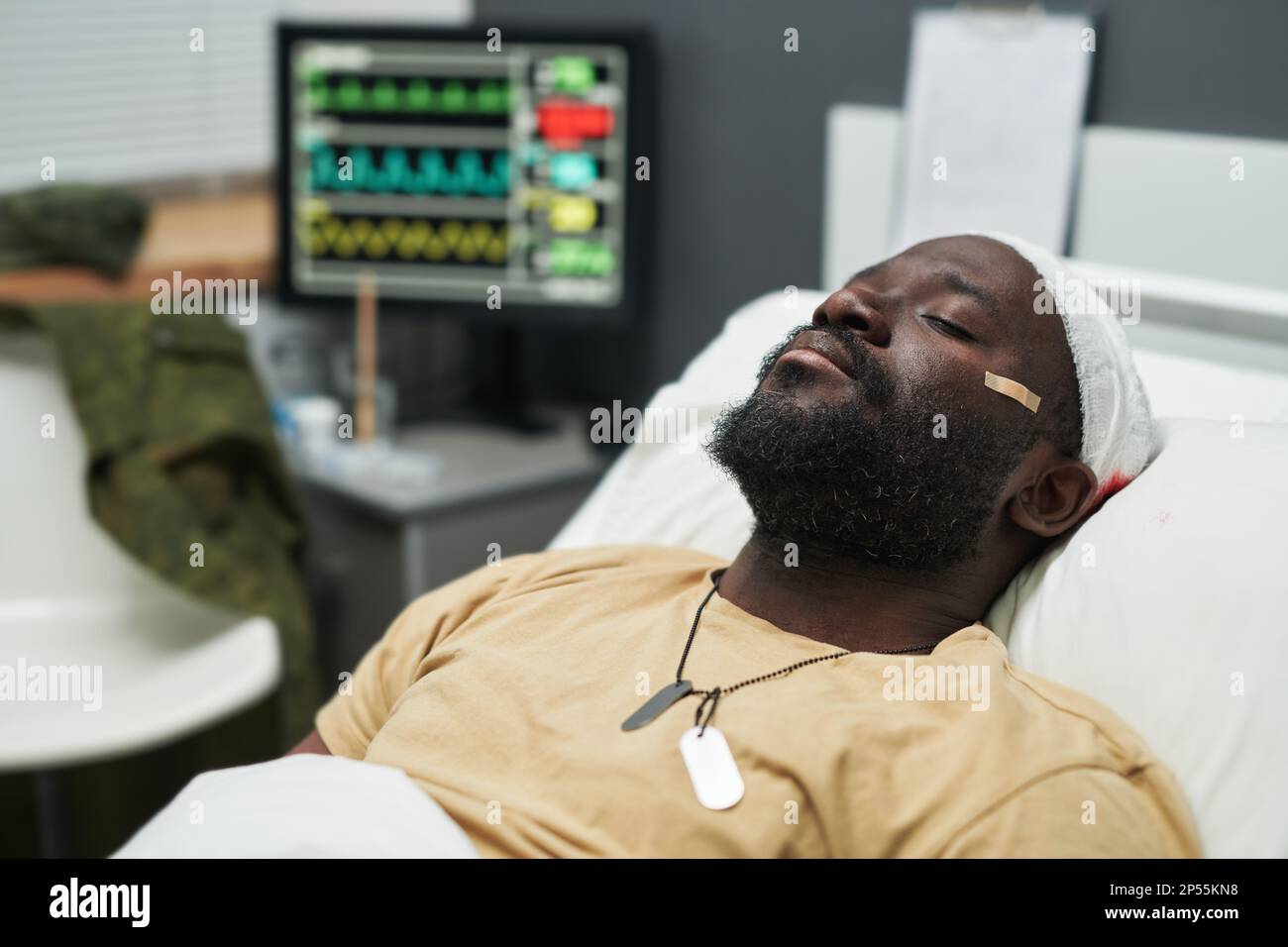 Close-up of young injured soldier with id tag on neck and bandage ...