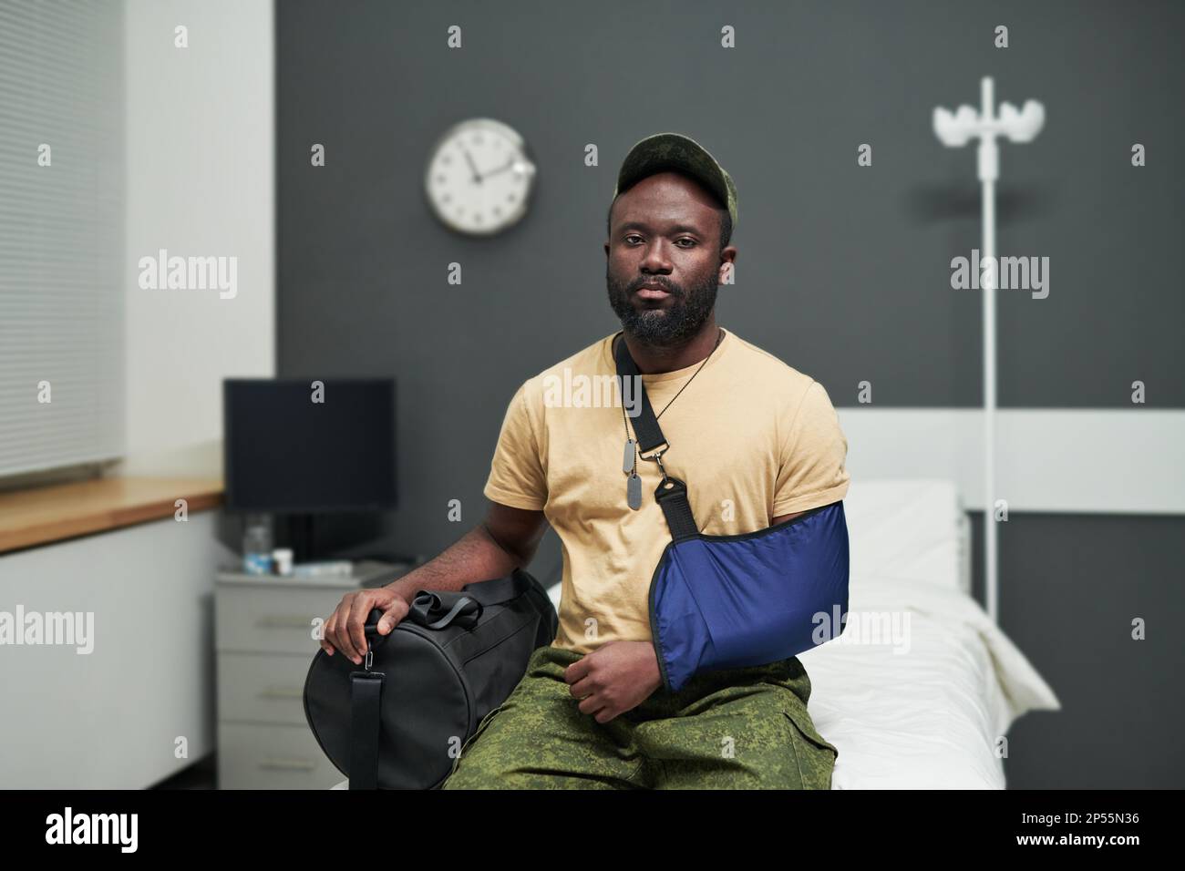 Young soldier with broken arm sitting in ward of military hospital ...