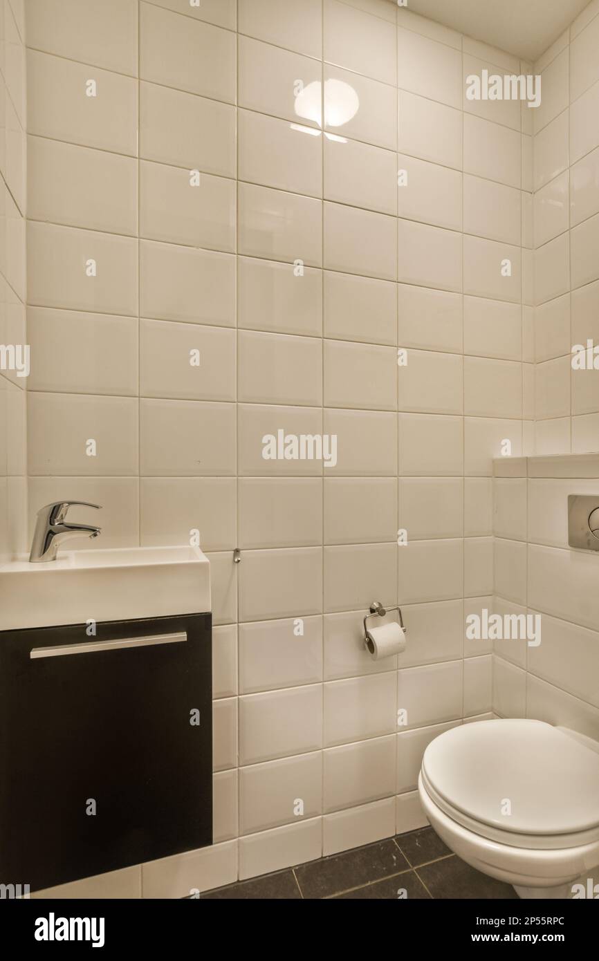 a bathroom with white tiles on the walls and black tile flooring around ...