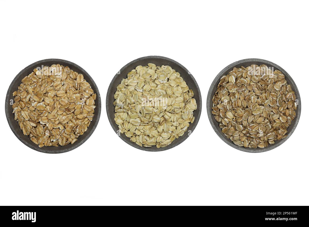 cereal flakes (spelt, oat, rye) in concrete bowls isolated on white ...