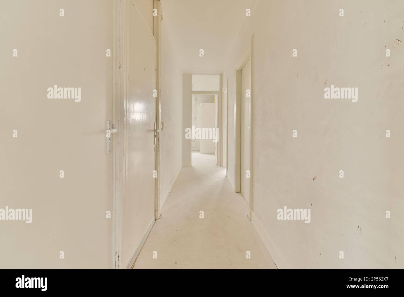 a long hallway with white walls and wood trim on the wall to the right ...
