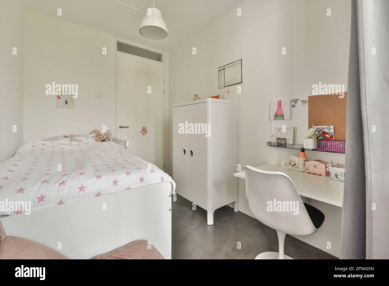 a girl's room with a bed, desk and white cupboards in the corner on the ...