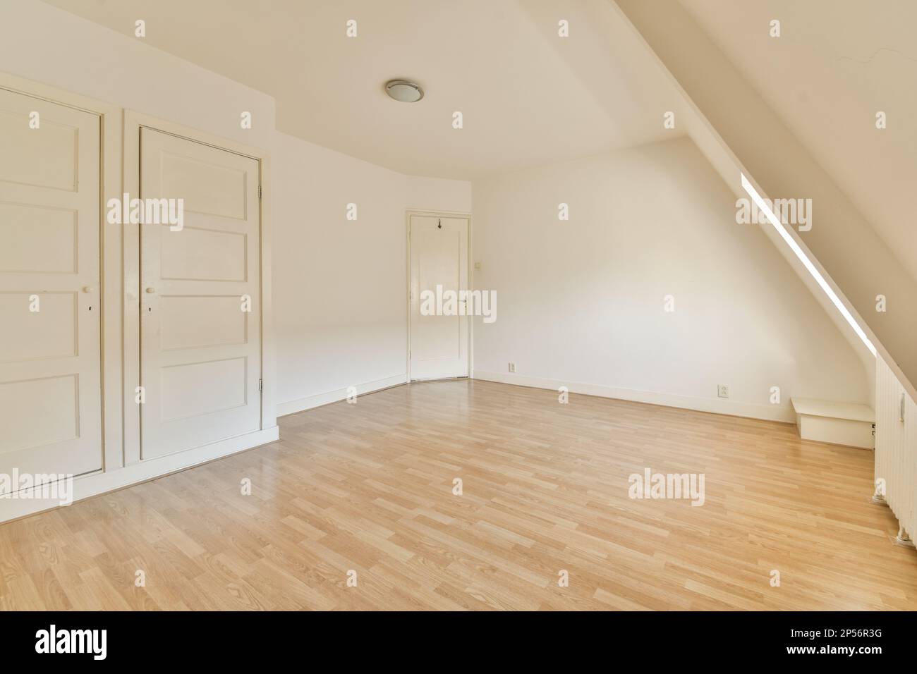 an empty room with wood flooring and white doord closets on the right ...