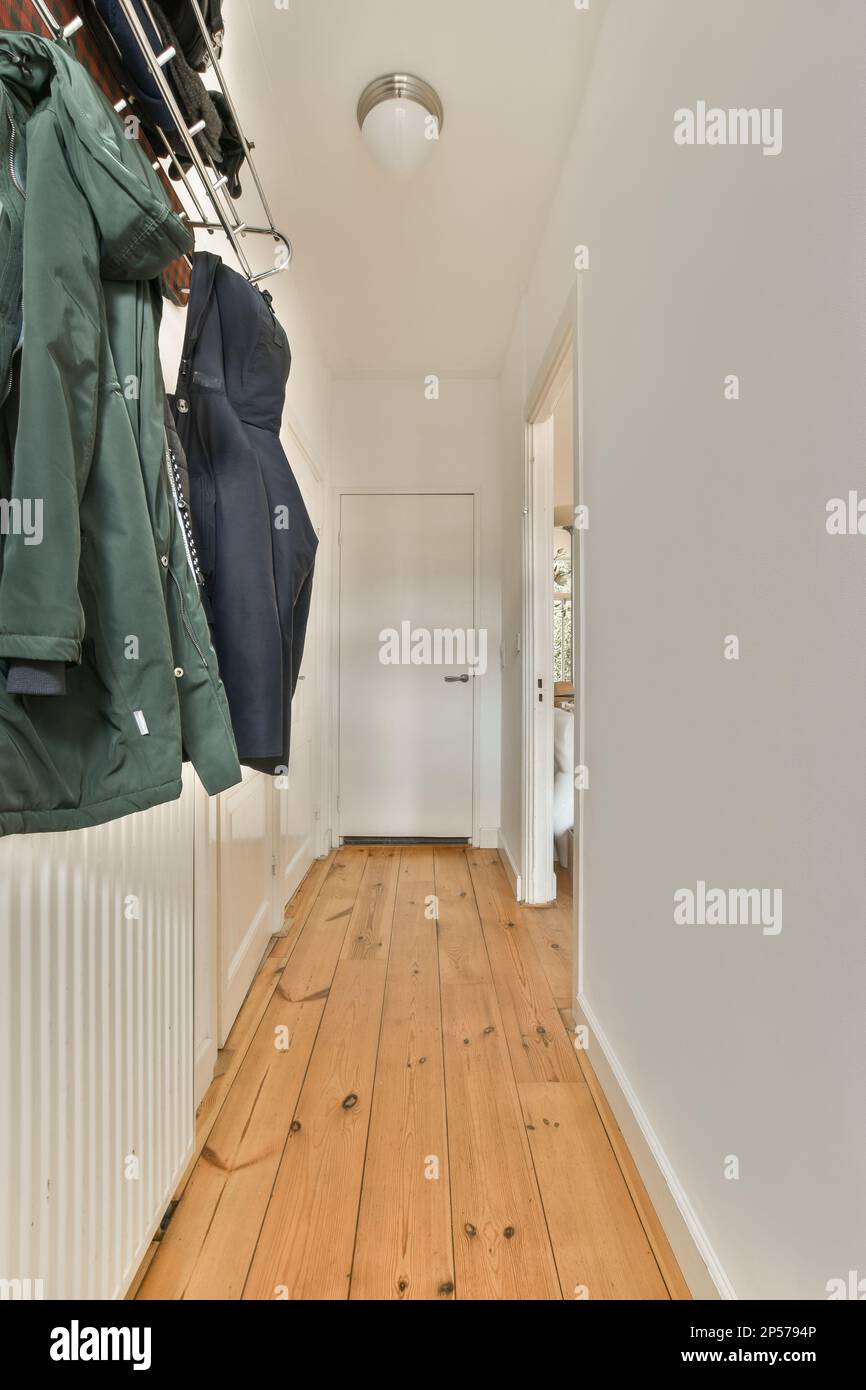 a hallway with wooden flooring and clothes hanging from the ceiling to ...