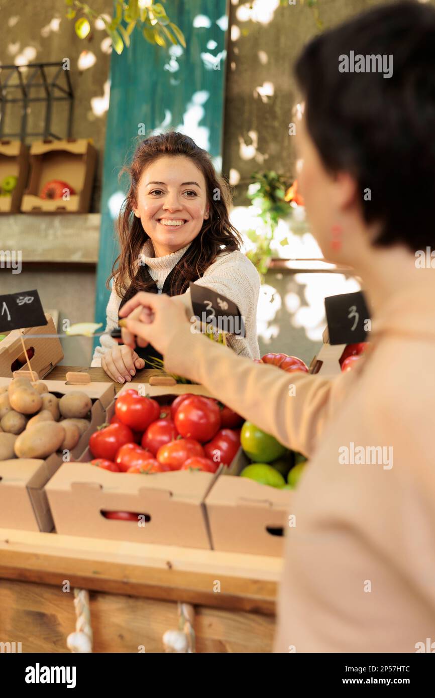 Friendly organic fruits and veggies shop owner offering clients to ...