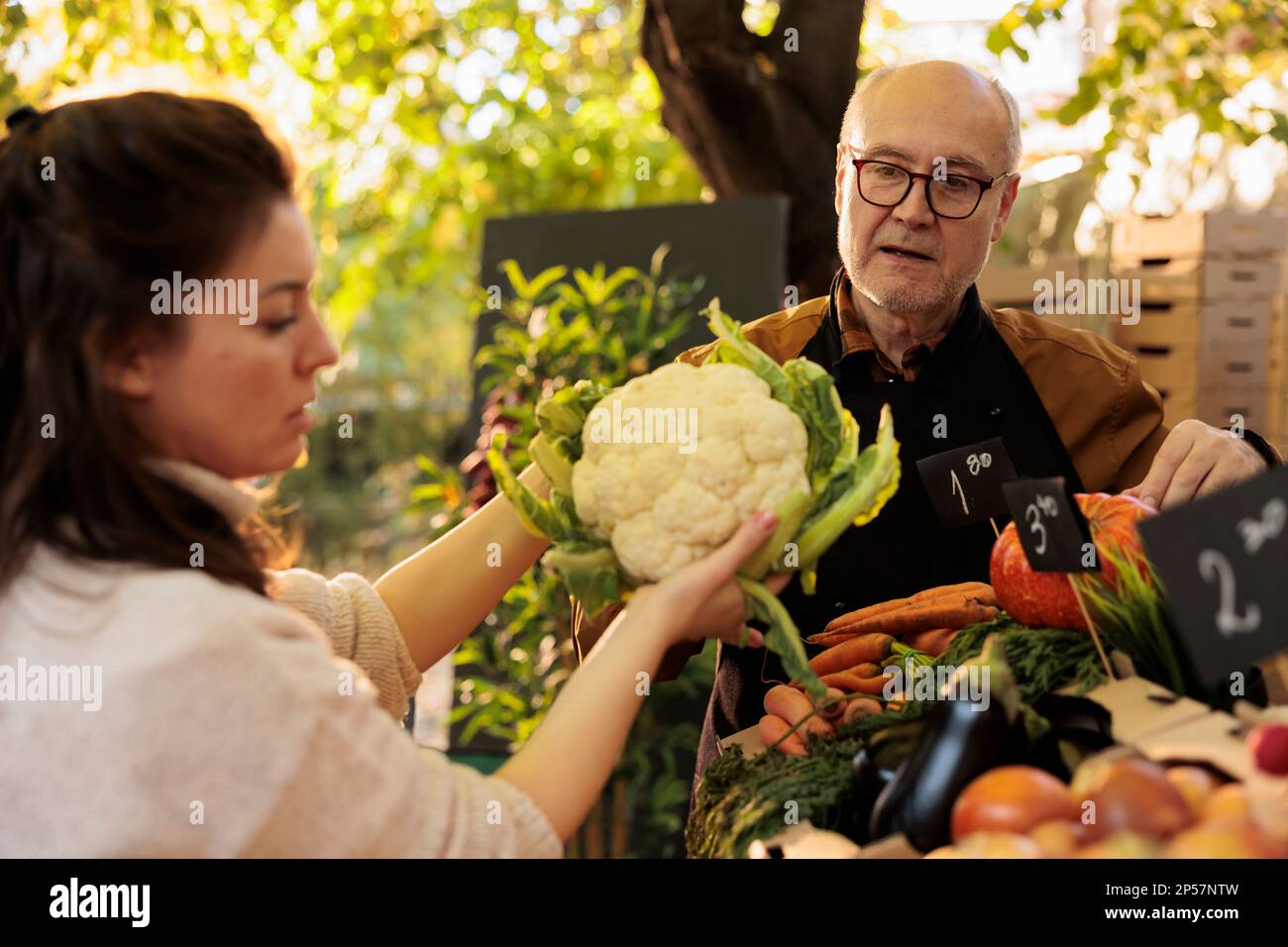 Young woman customer holding cauliflower while buying fresh locally ...