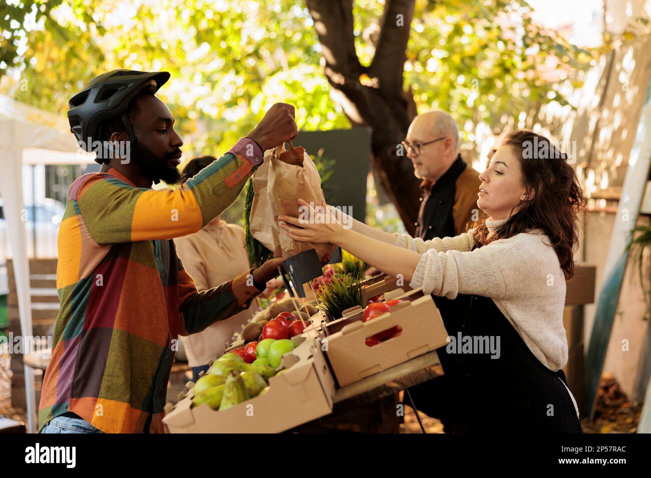 Female small business owner giving order of fresh produce to african ...