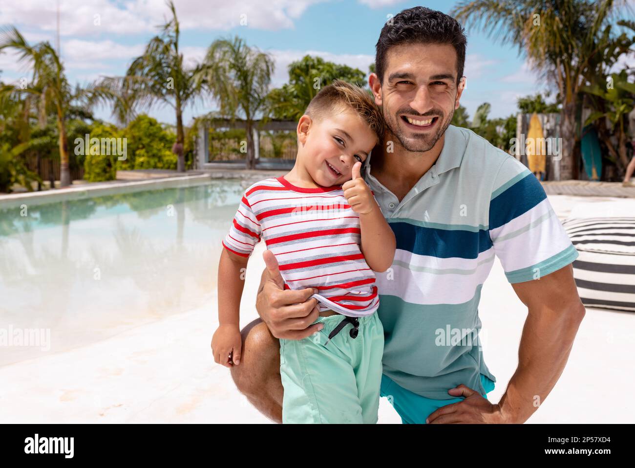 Portrait of happy biracial father and son embracing by the swimming ...