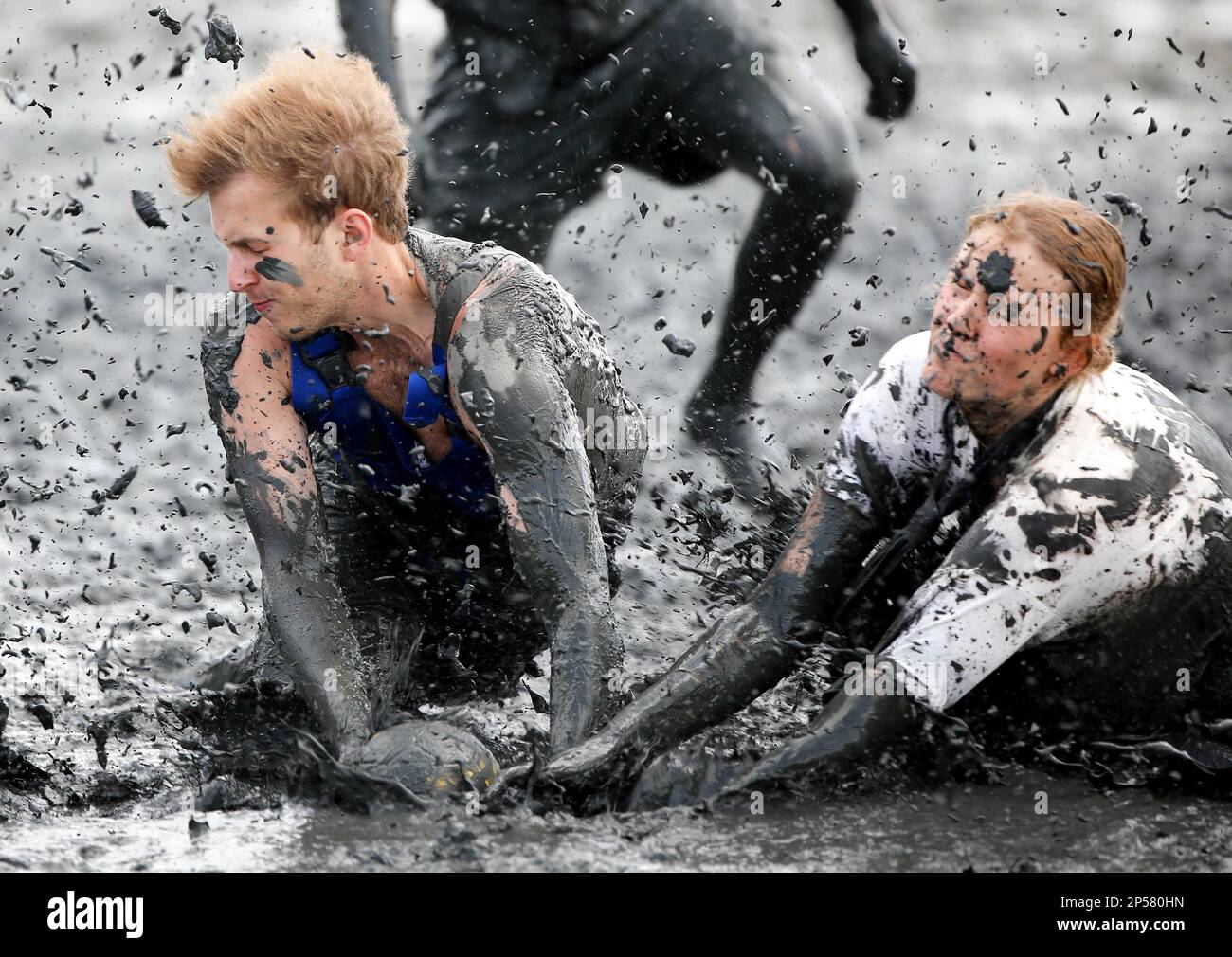 Participants of the ' Mudflat Olympics' play a ball game in the mud in ...