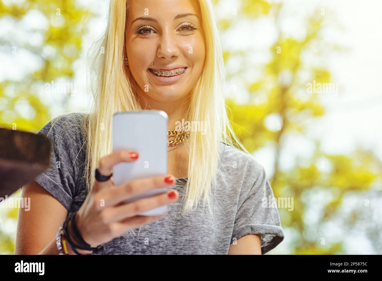 Beautiful Smiling Blond Girl In An Outdoor Forest Or Public Park On A Sunny Day She Has Very