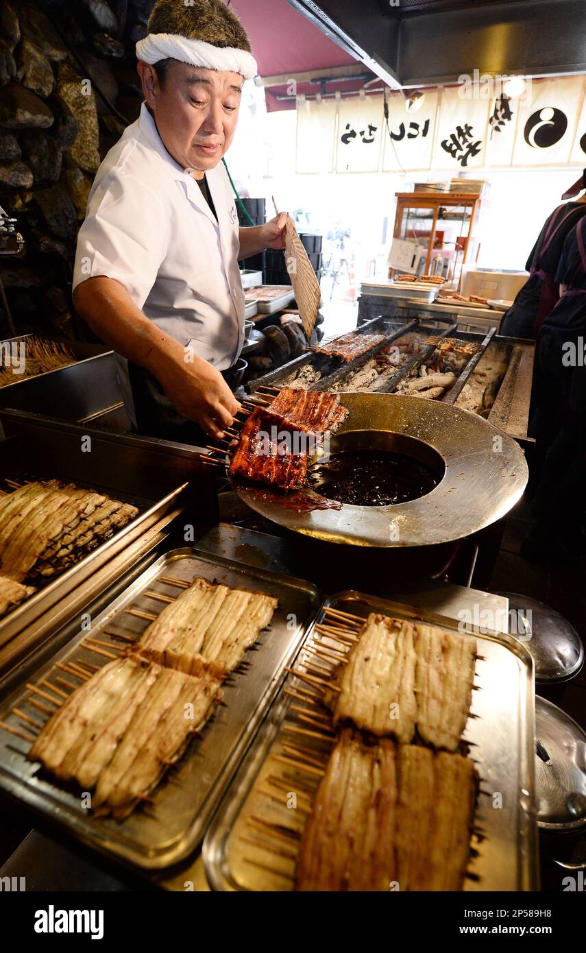 A man broils skewered eels at Yatsume-ya unagi, an eel shop for Doyo no ...