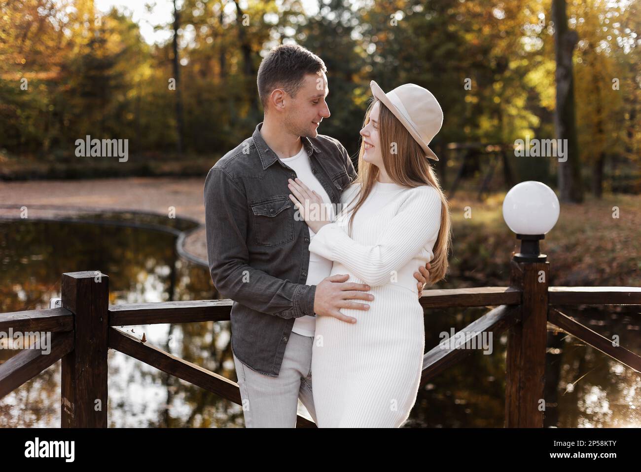 Happy stylish pregnant woman and man hugs, kiss, touches belly and ...